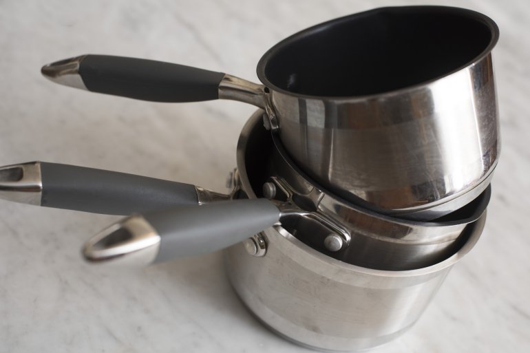 Stack of clean metal pans on a kitchen table - Free Stock Image